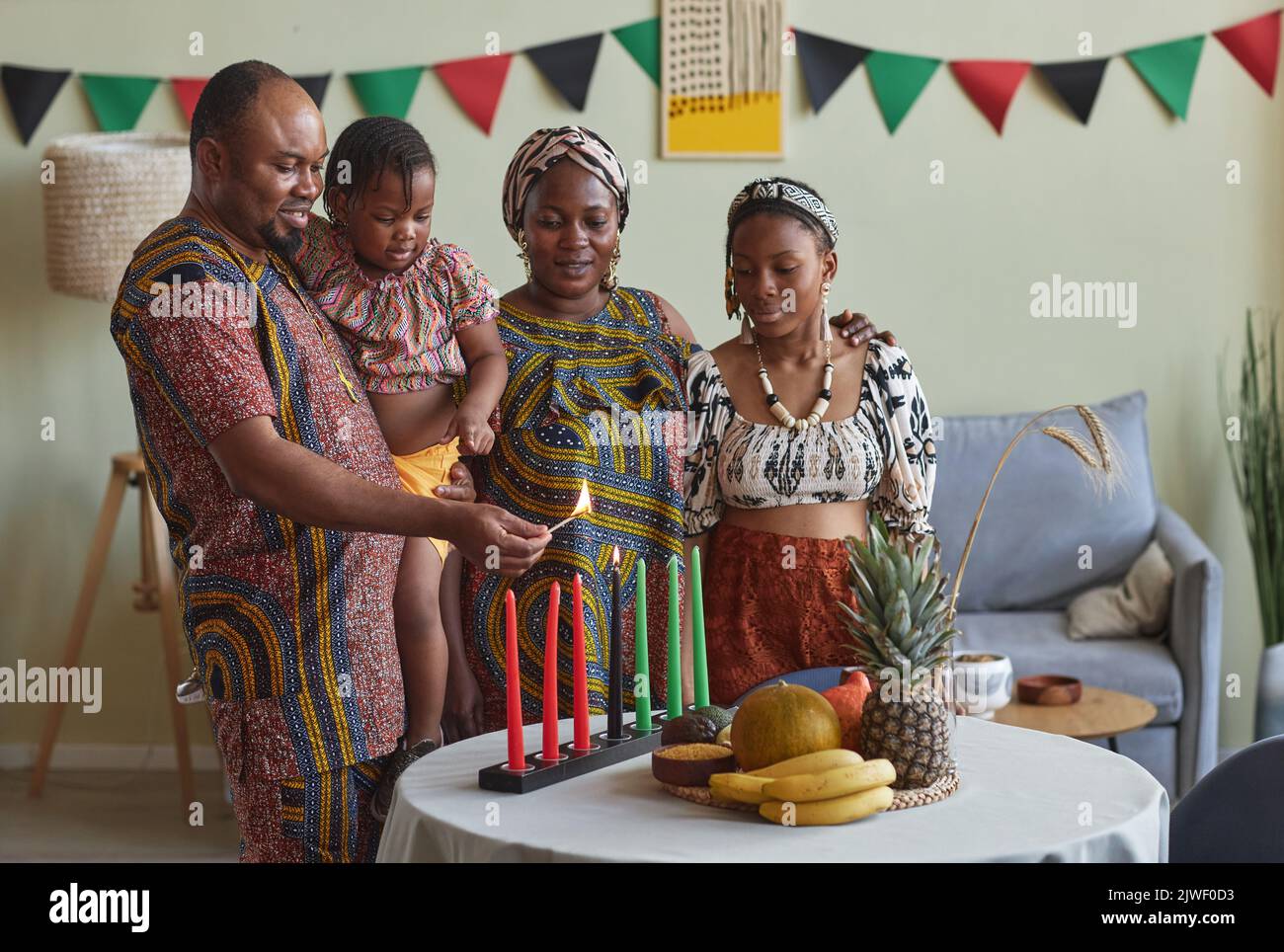 African family of four burning candles together to celebrate Kwanzaa ...