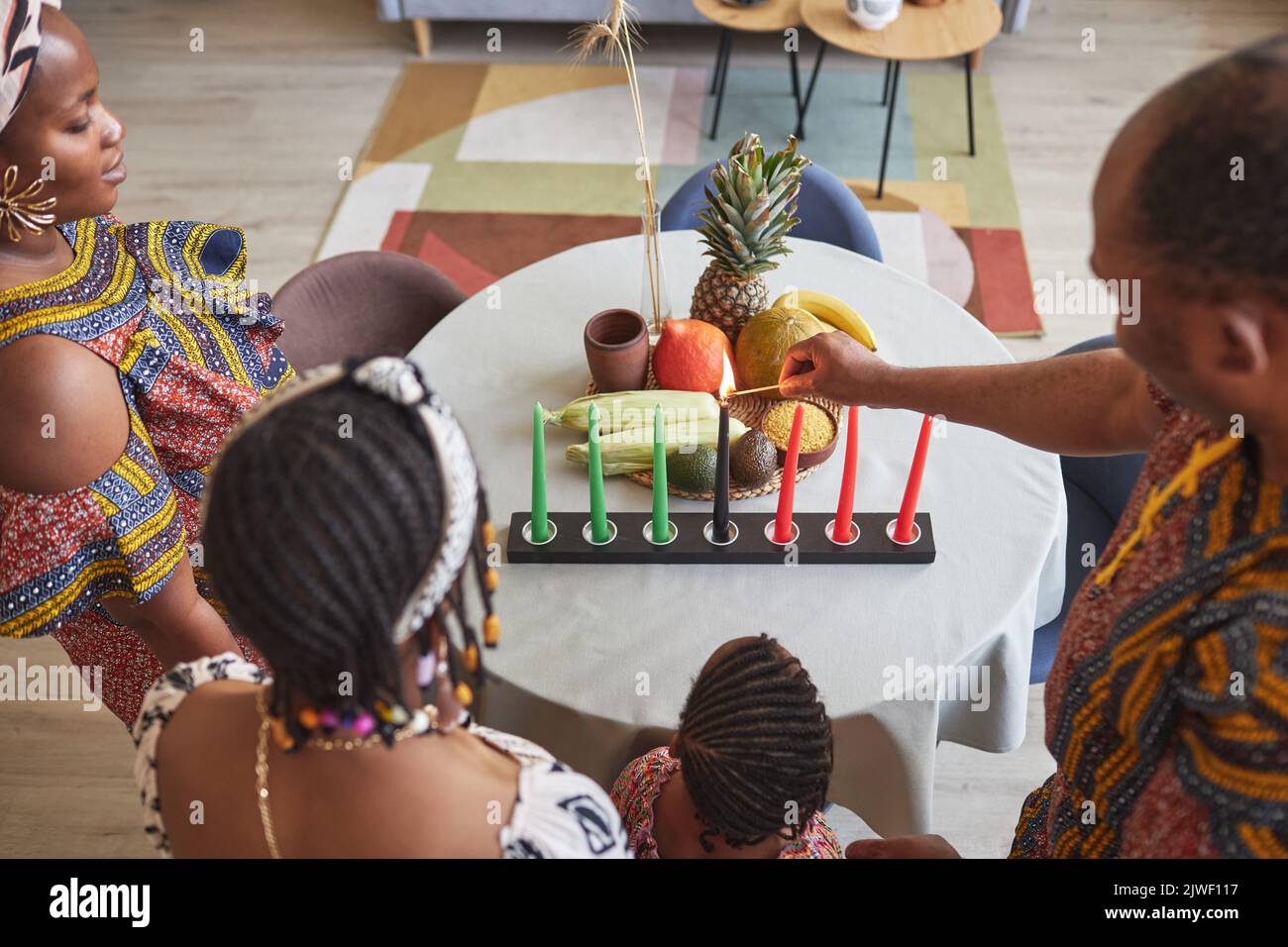 Rear view of African family burning seven traditional candles while ...