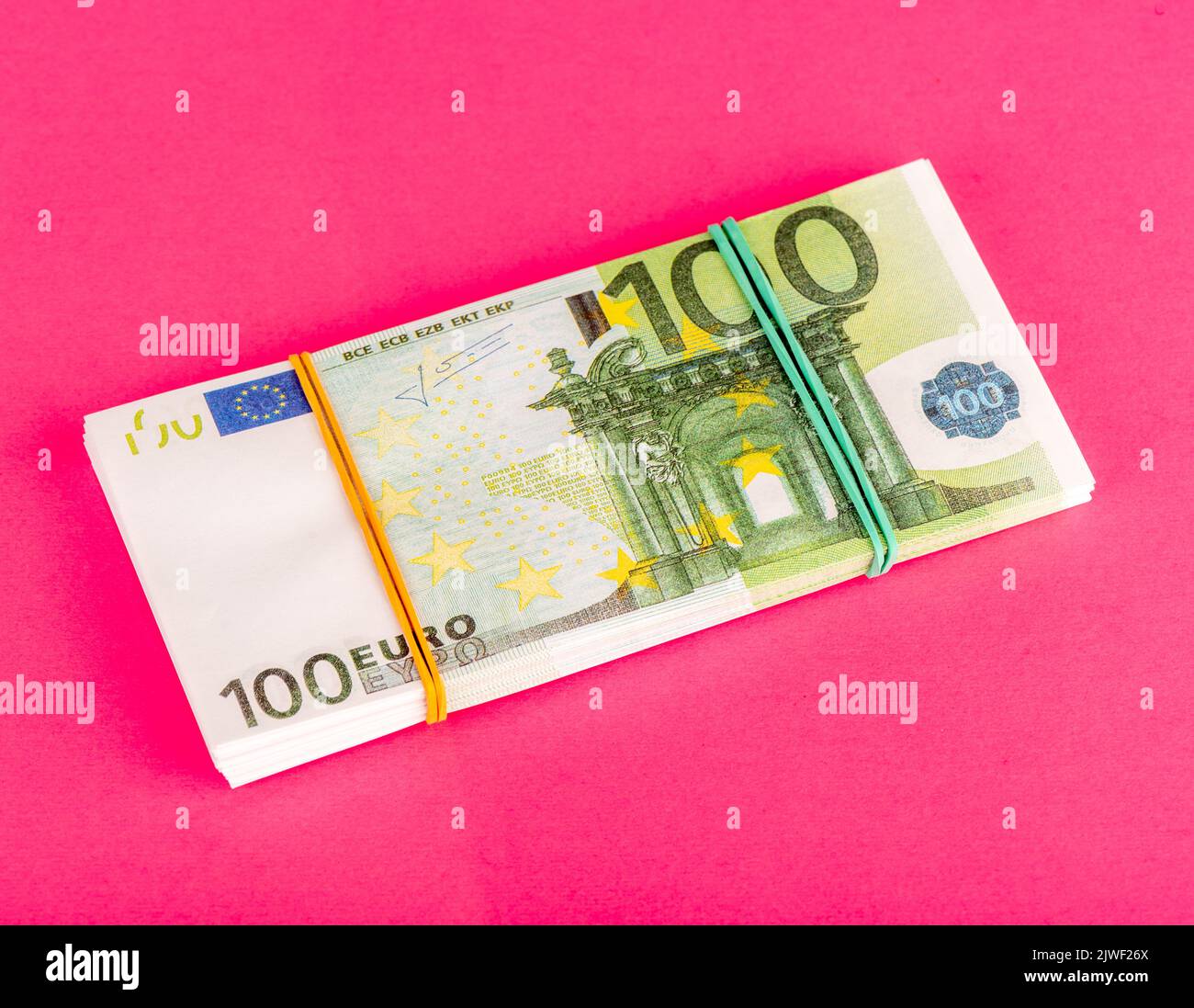 Stack of one hundred euro banknotes is tied with yellow and green ...