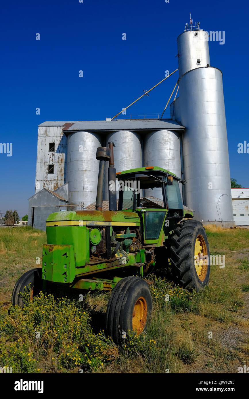 Grain elevator and tall storage silos with old green tractor Stock ...