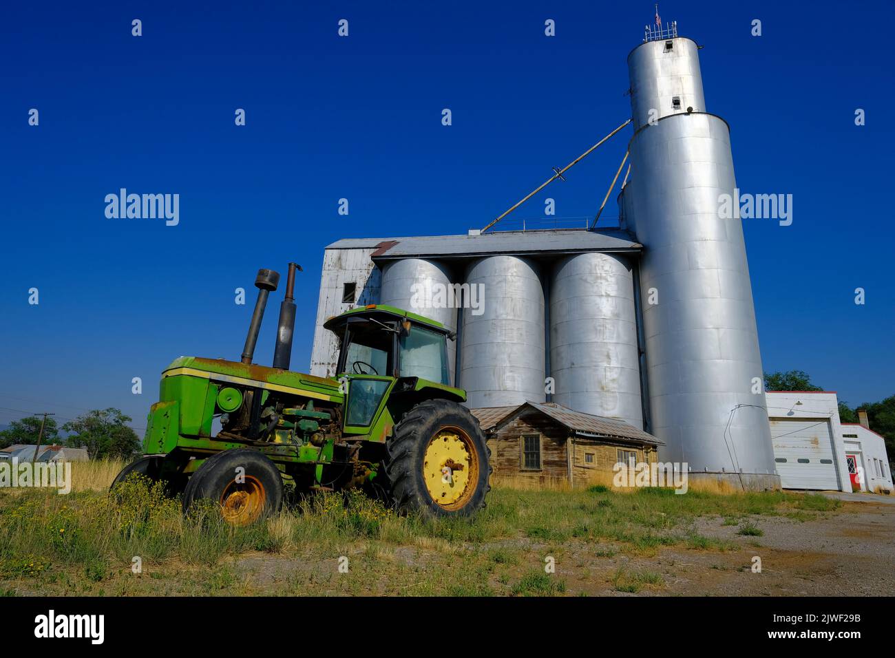 Grain elevator and tall storage silos with old green tractor Stock ...