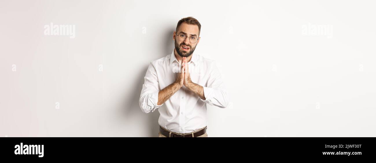 Worried man asking for help, begging for favour, standing over white ...