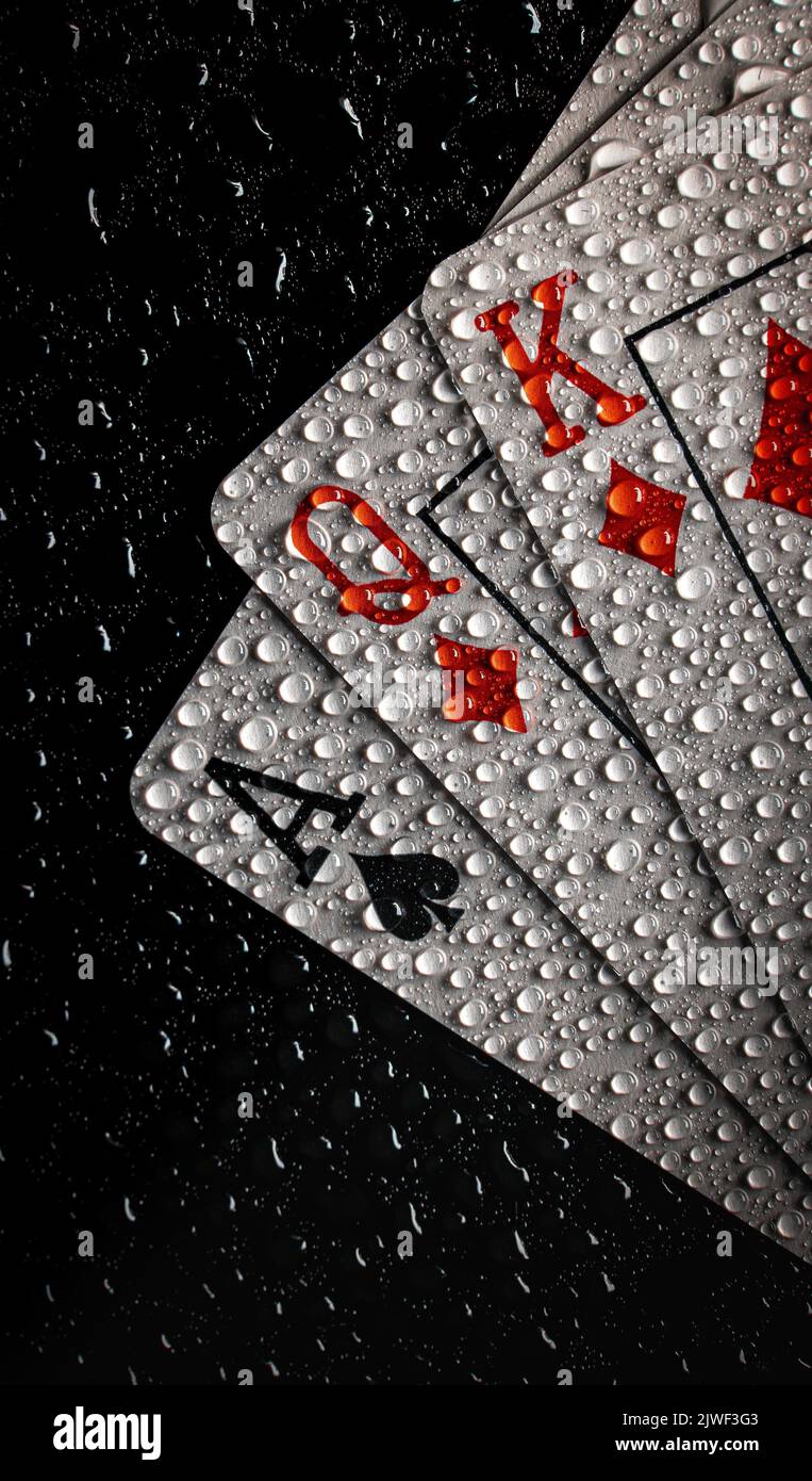 a vertical shot of ace, queen, and king cards with water droplets ...