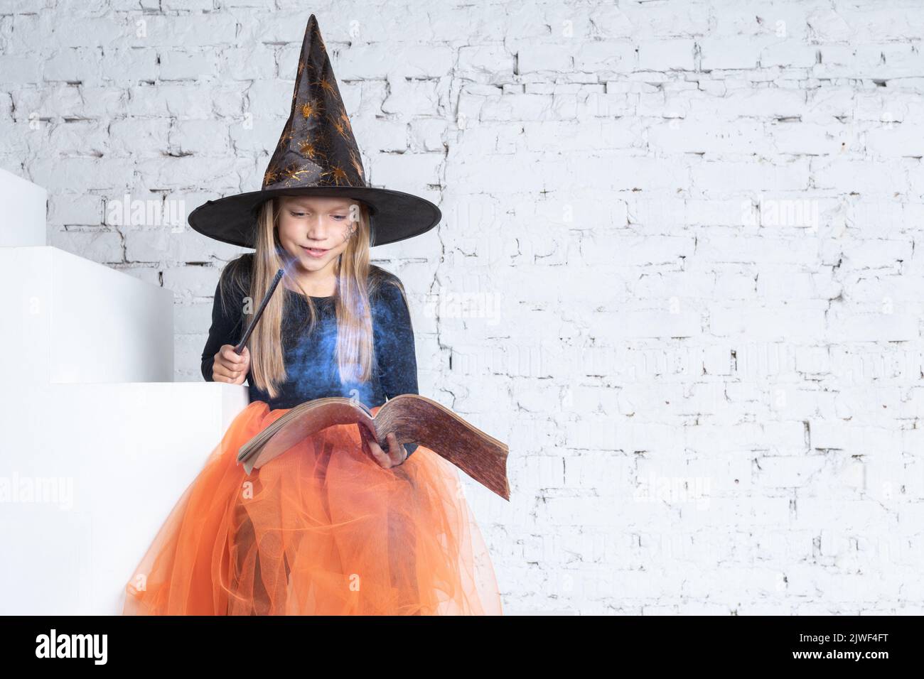 Kids Halloween. A beautiful sweet girl in a witch costume, wearing a ...