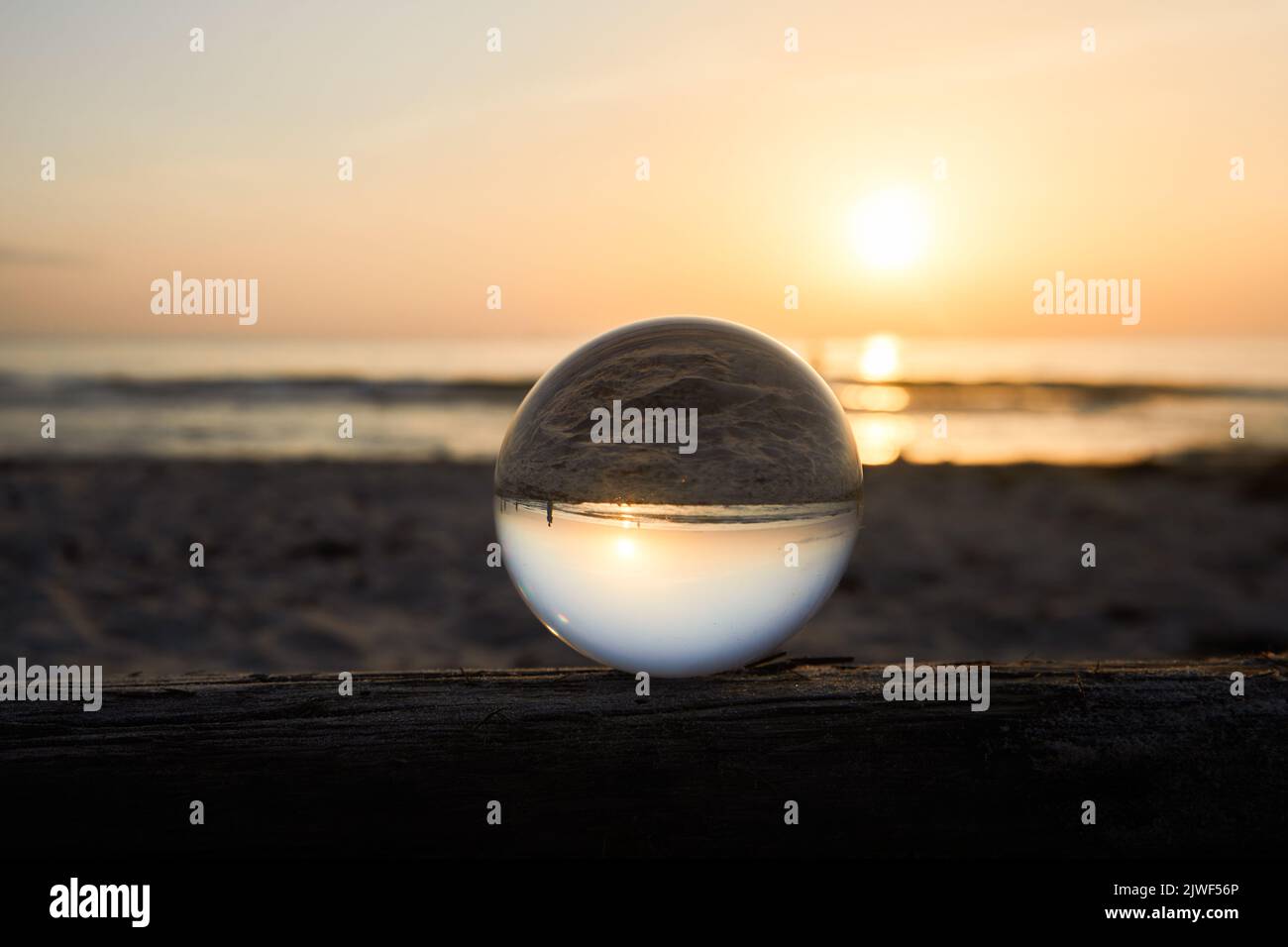 View on a sunset over ocean coast through a glass ball. Selective focus ...