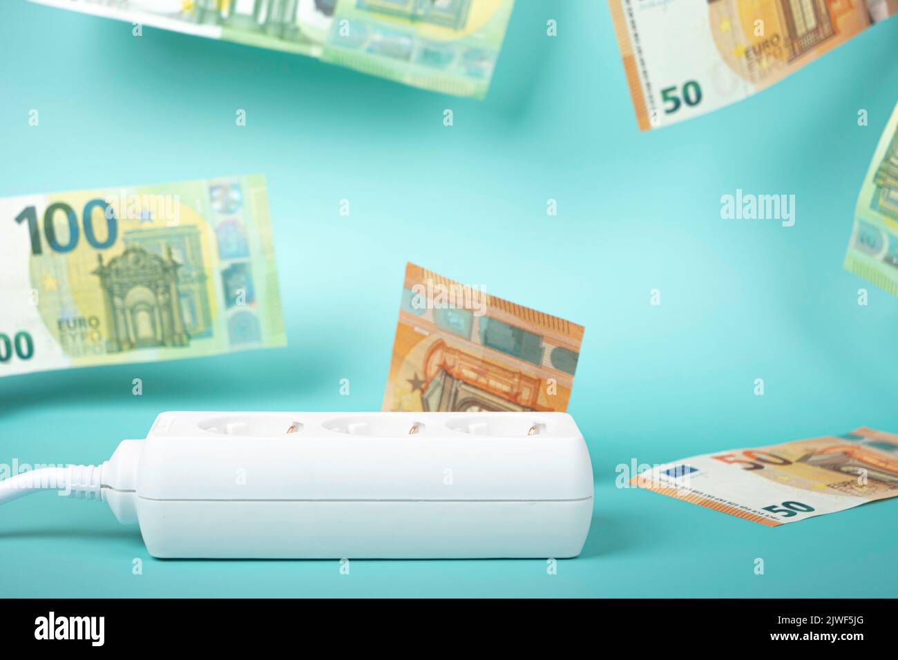 Euro money banknotes falling into power strip extension cord over light ...