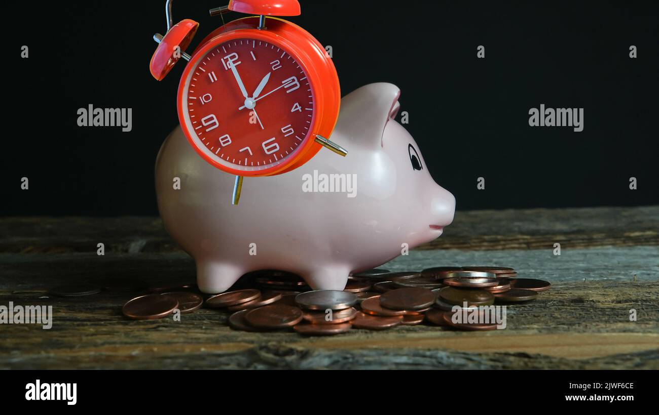 Clock with pink piggy saving bank Stock Photo - Alamy