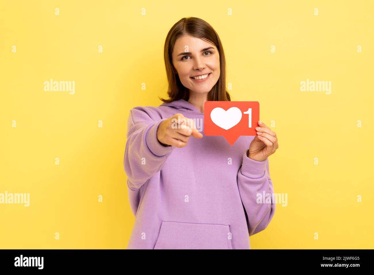 Portrait of dark haired positive woman blogger holding hear like icon ...