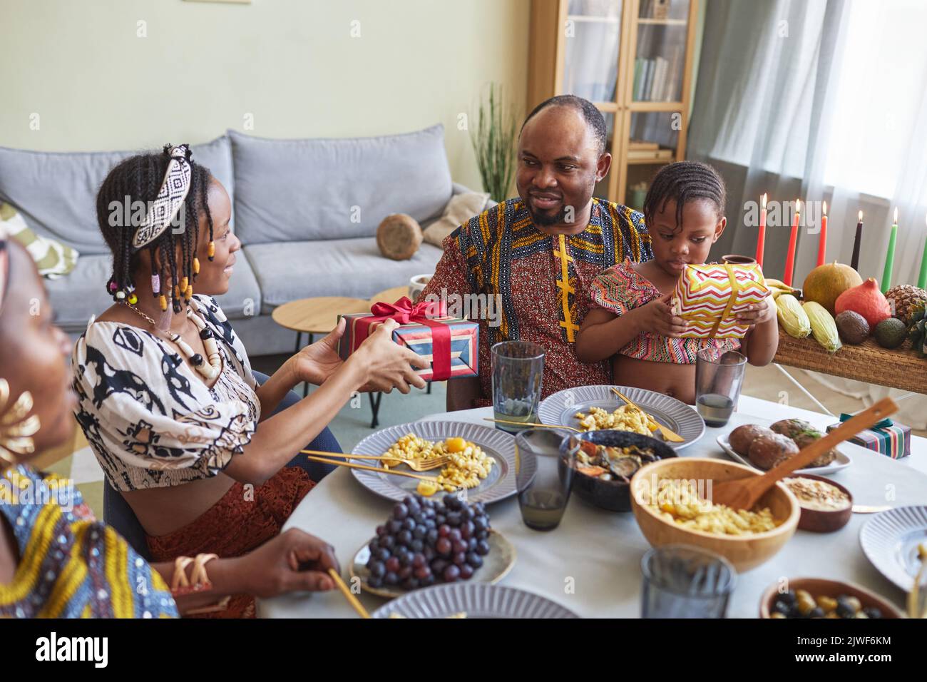 African family giving presents to each other during holiday dinner at ...