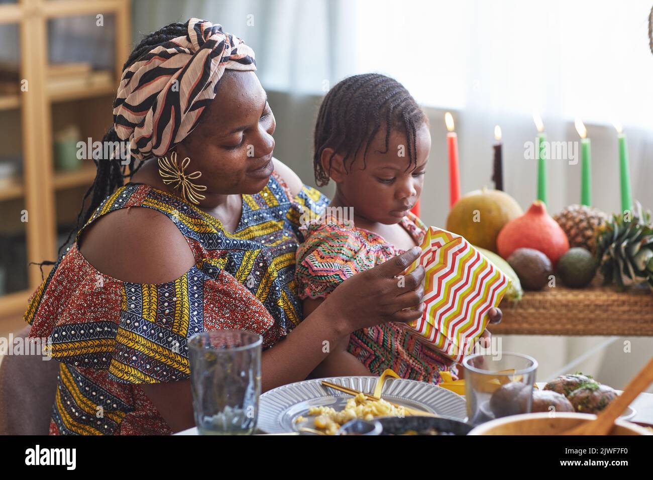 African woman in national costume opening present with her little ...