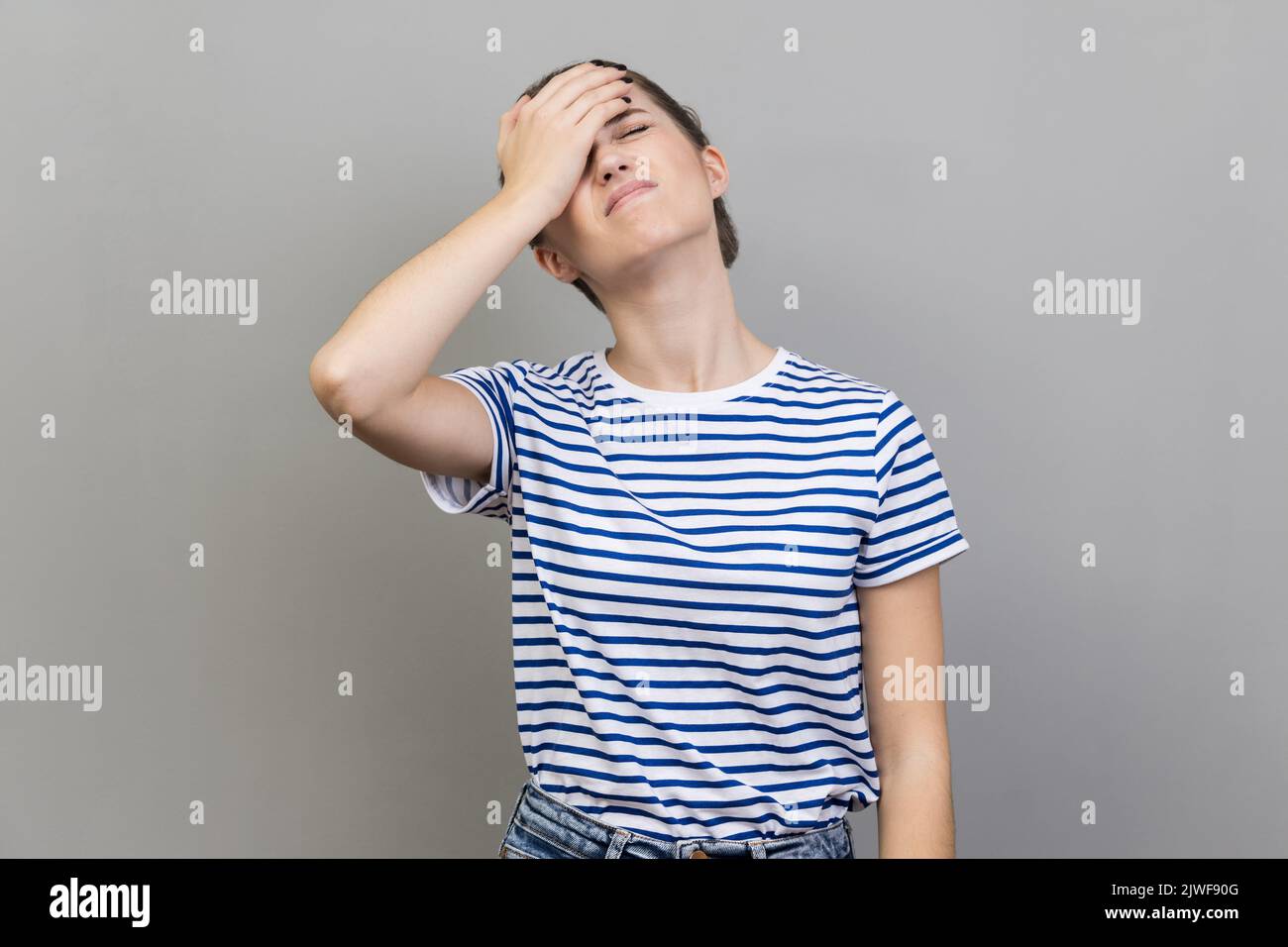 Portrait of upset frustrated woman wearing striped T-shirt holding ...