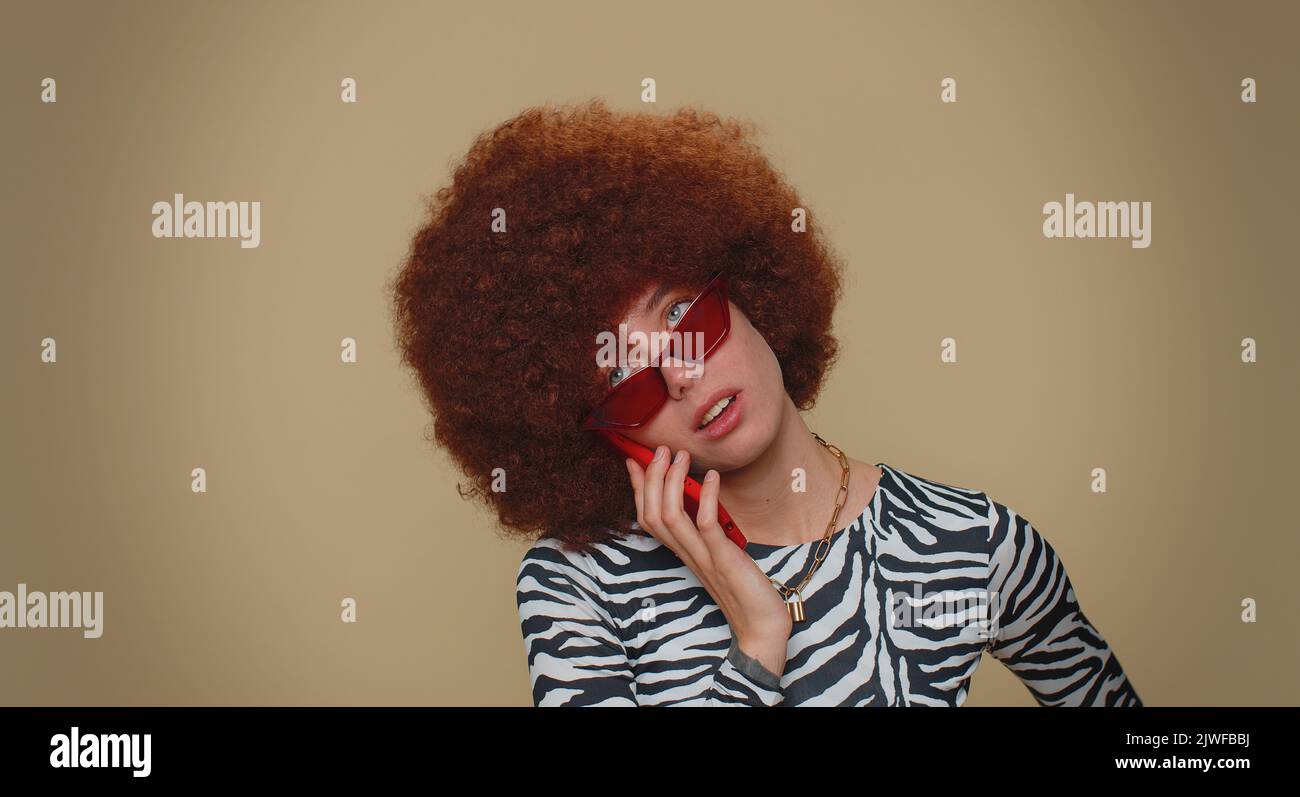 Tired young woman with brown lush wig making online conversation speaks ...