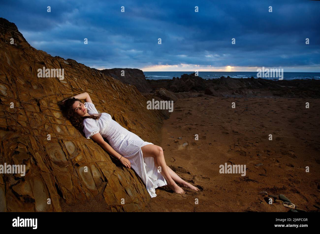 A beautiful woman with wild hair on Widemouth bay beach on a stormy ...