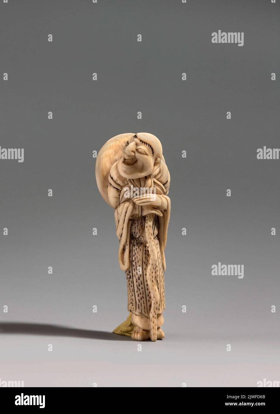 Netsuke in the shape of laughing pilgrim monk leaning on a staff, with ...