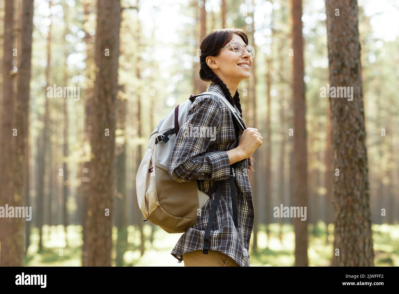 Young girl with backpack enjoying her hiking in the forest in summer ...
