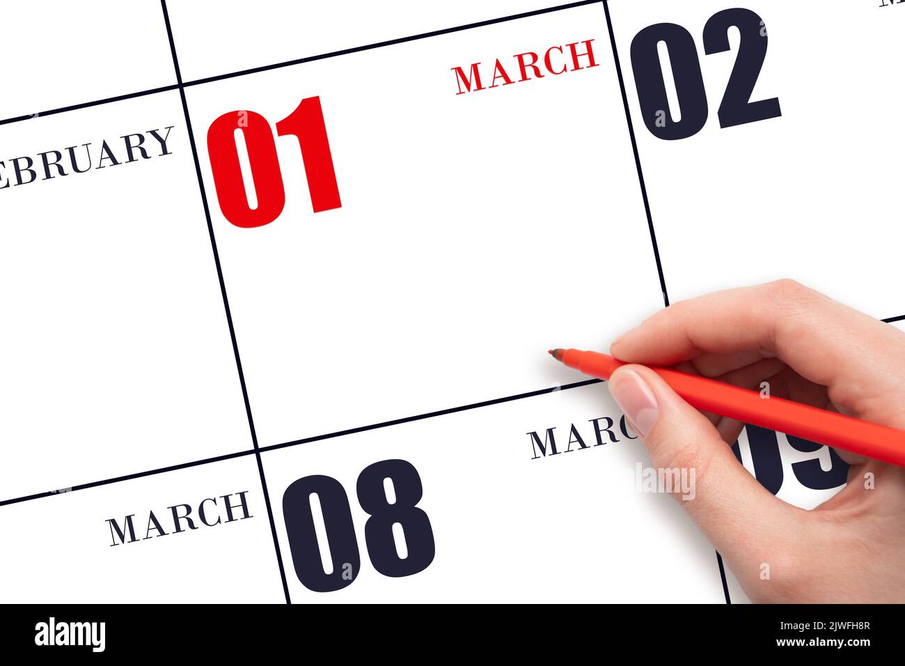 1st day of March. A hand holding a red pen and pointing on the calendar ...