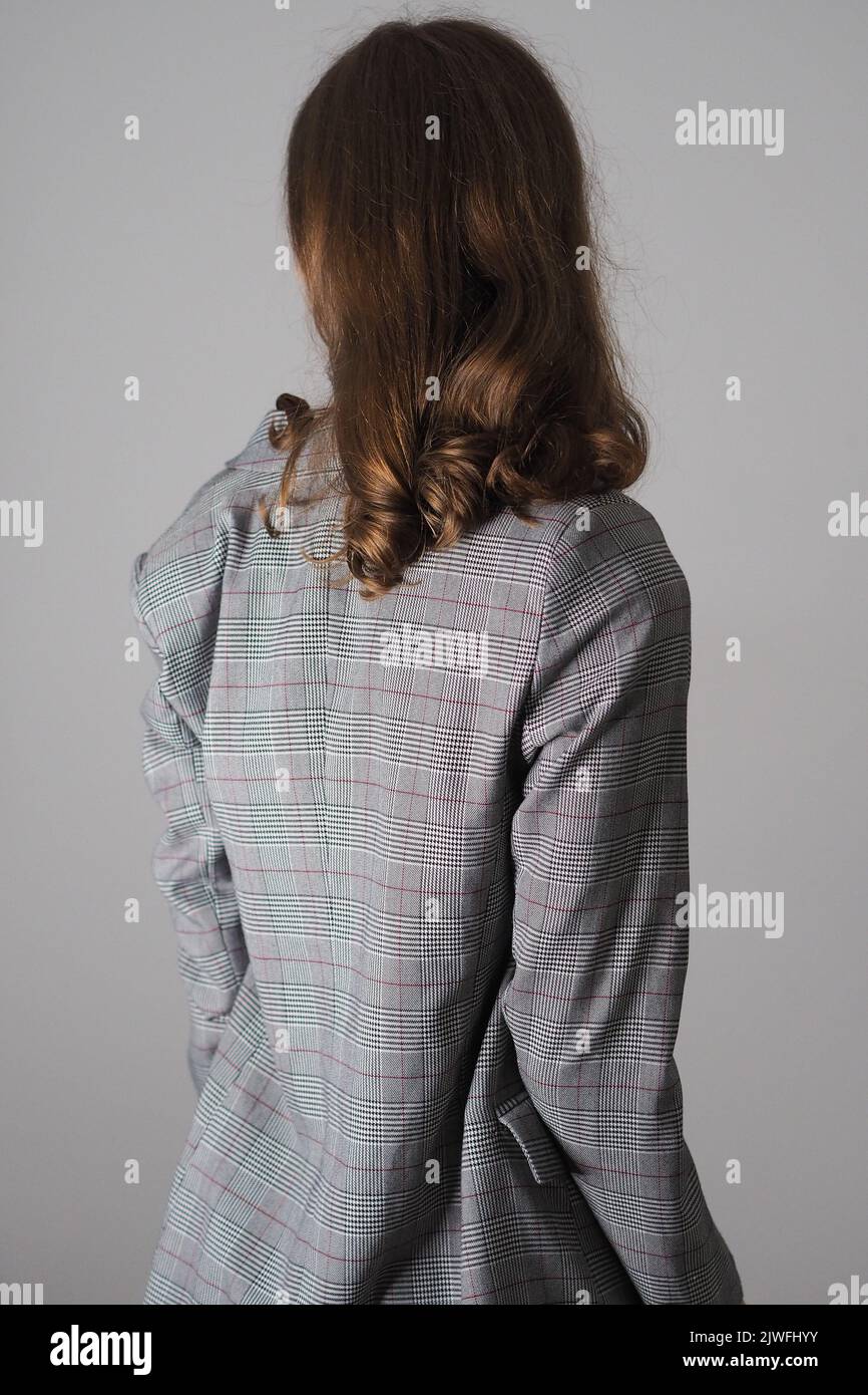A vertical shot of a female from behind wearing a winter coat isolated ...
