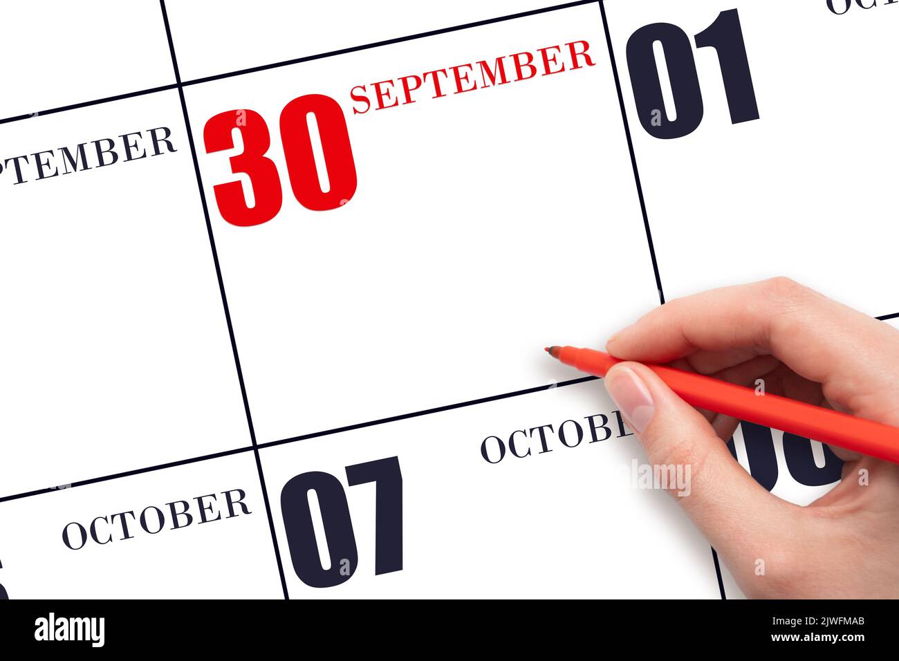 30th day of September. A hand holding a red pen and pointing on the ...