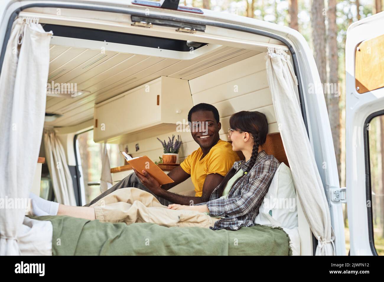 Young multiethnic couple resting in house of wheels, they sitting on ...