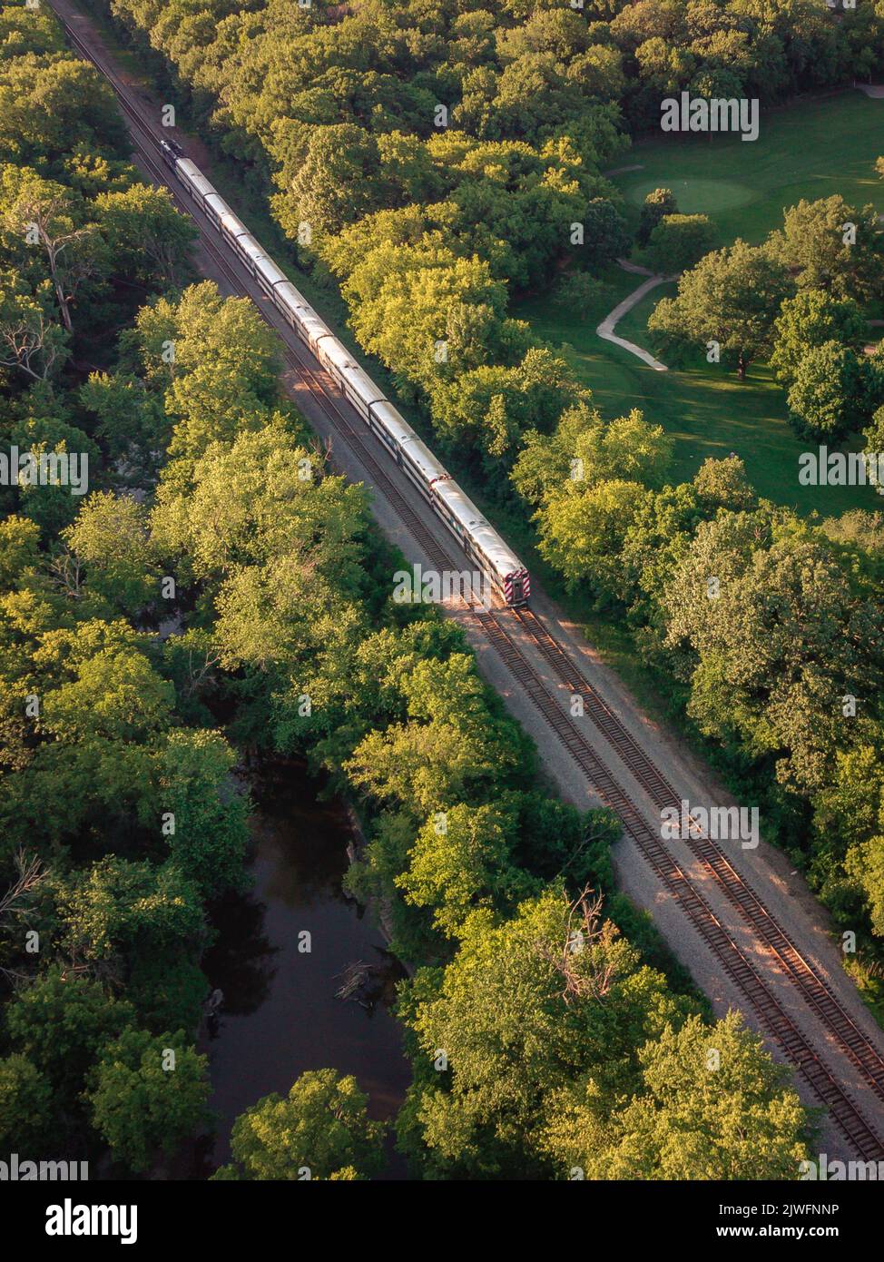 A vertical aerial view of a train driving along the tracks surrounded ...