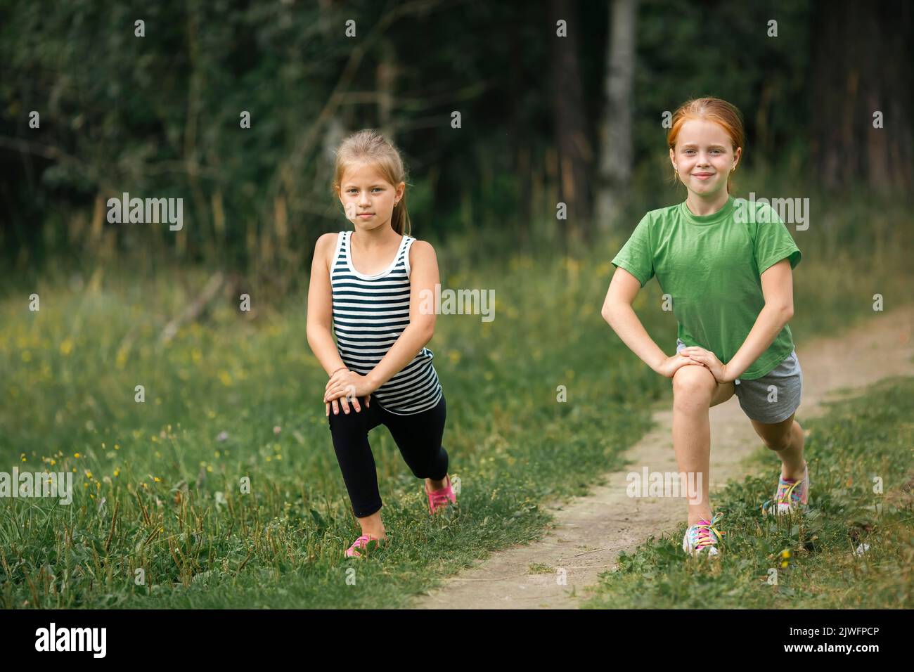 Two Ten year old Girls Warming Up Before A Jog In The Park Stock Photo two-ten-year-old-girls-warming-up-before-a-jog-in-the-park-stock-photo