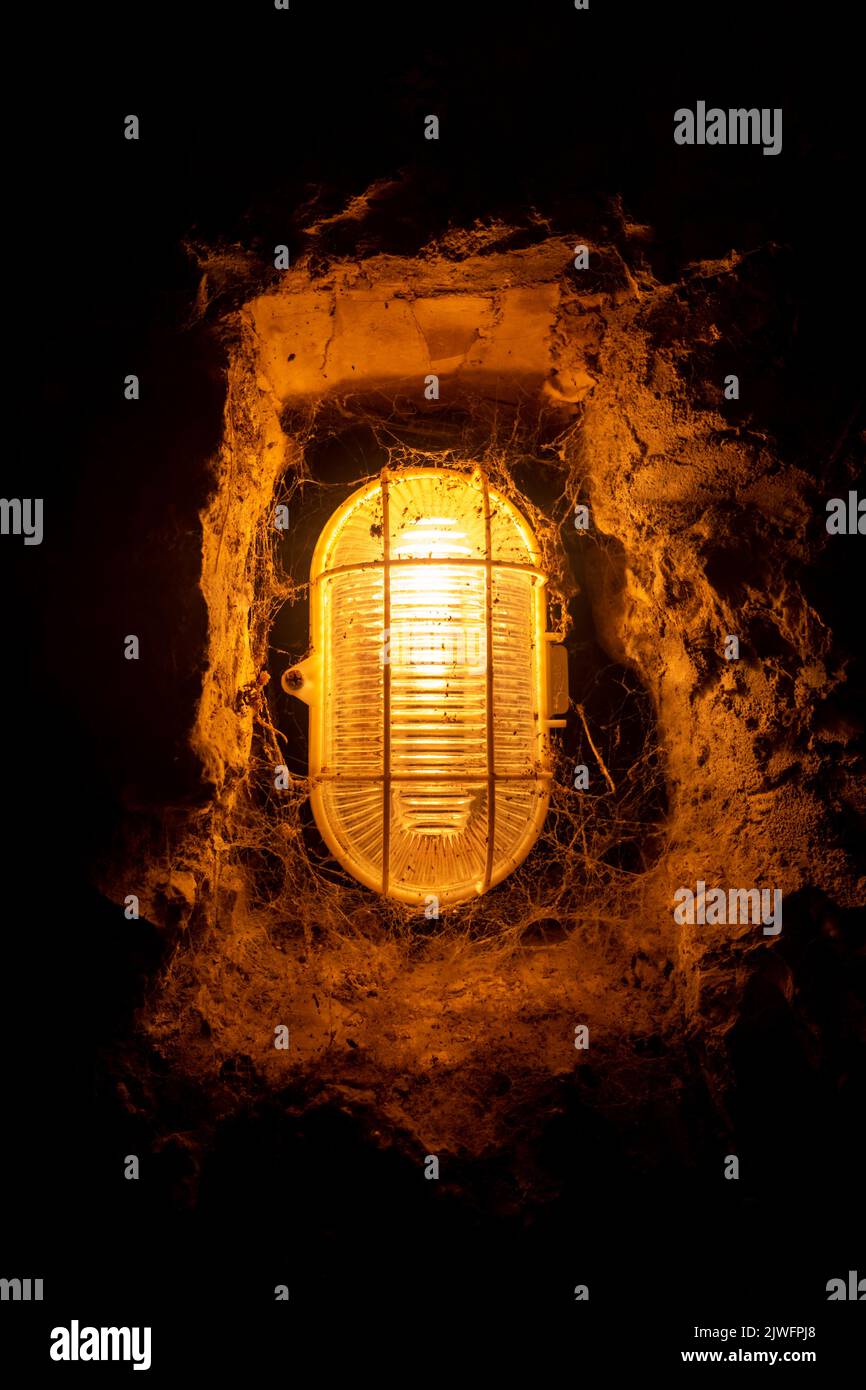 A wall lamp embedded in the rock of a tunnel illuminates the passage ...