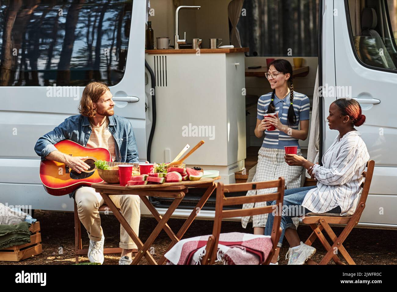 Group of young friends having picnic in nature in the forest, they ...