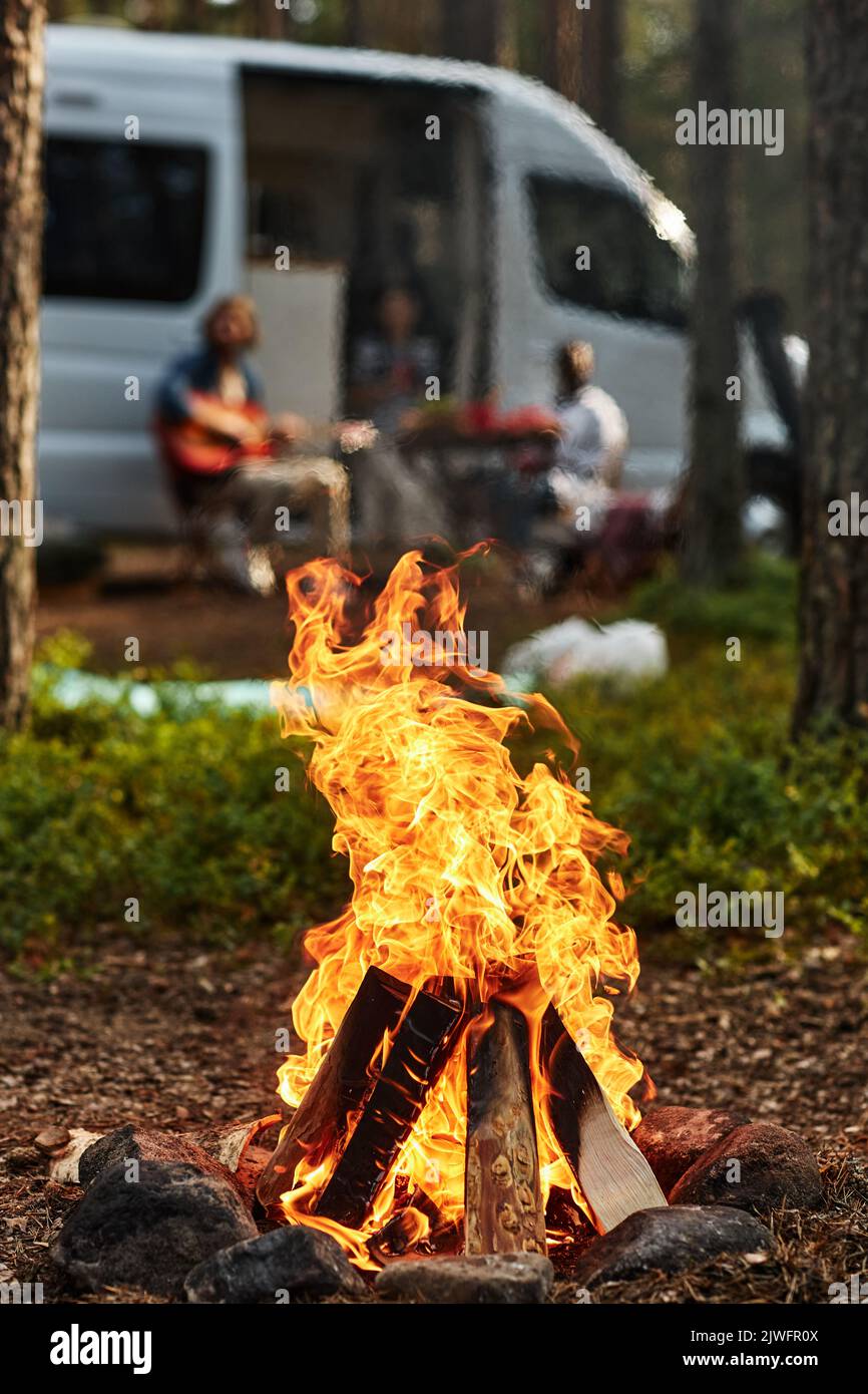 Close-up of bonfire during camp in the forest with young people playing ...
