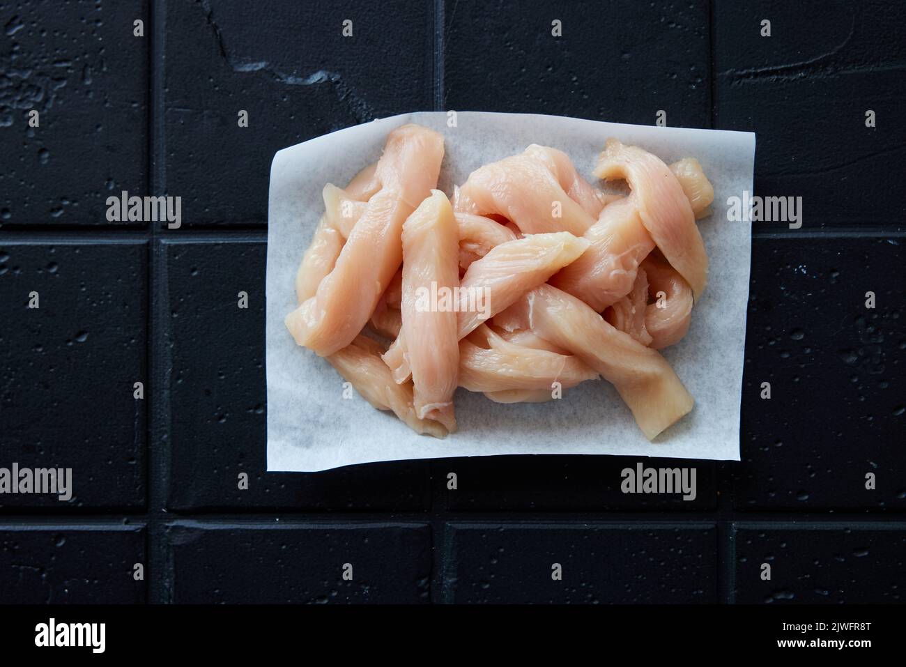 Top view of uncooked fresh chicken strips on white napkin placed on ...