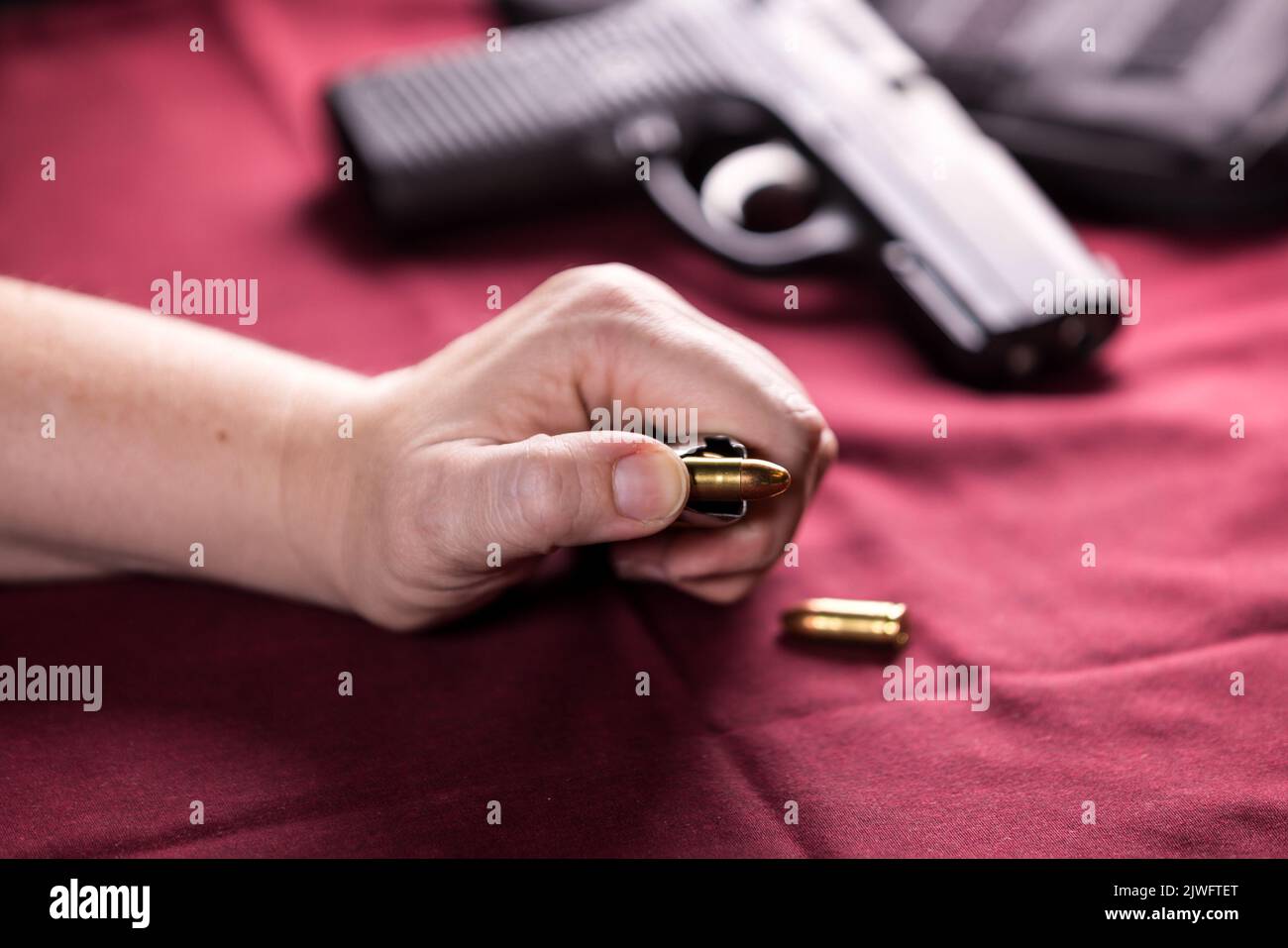 Hand holding a pistol magazine pushing bullets free with the thumb ...