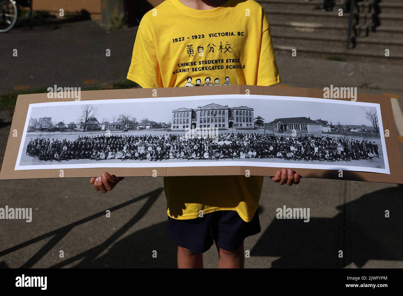 A boy holds a picture from 1921 of George Jay School class photo as a ...