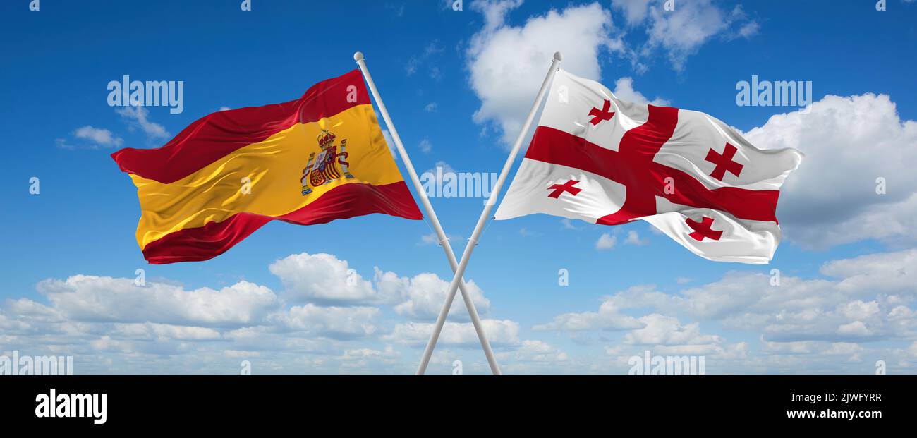two crossed flags Georgia and spain waving in wind at cloudy sky ...