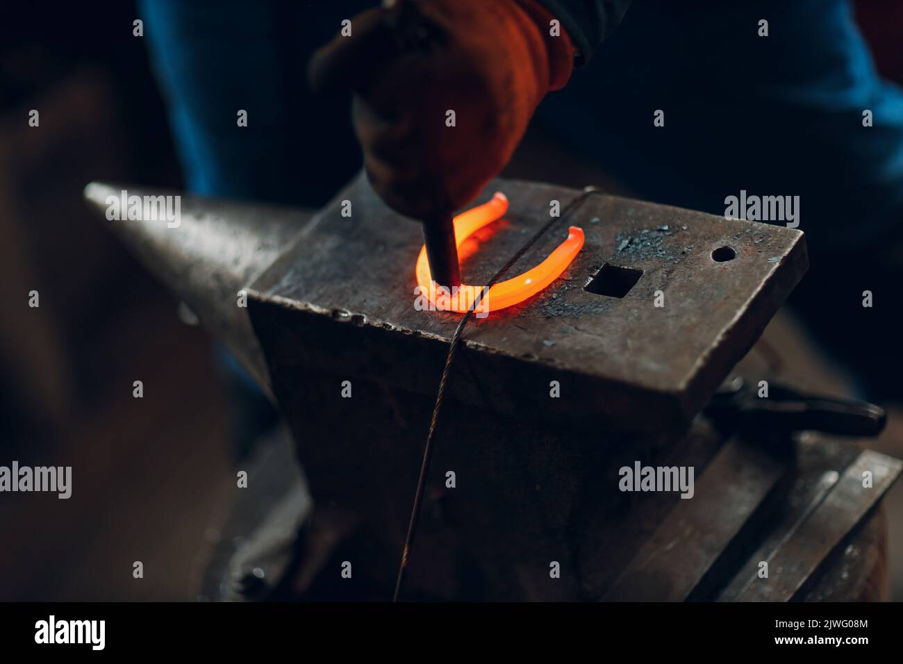 Blacksmith forges and making metal horseshoe with hammer and anvil at ...