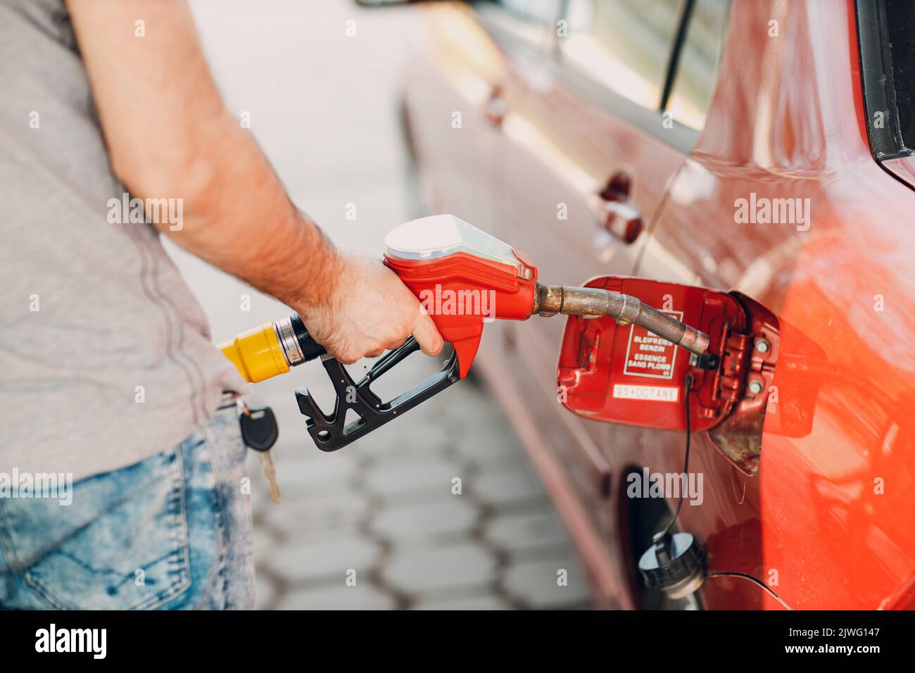 Man filling fuel tank in his hand at gas station Stock Photo - Alamy