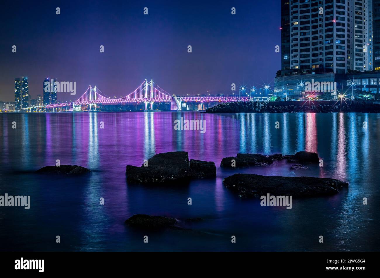 The rocks in a river with illuminated Diamond Bridge of Busan city in ...