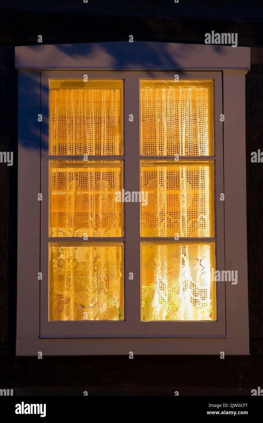 Light on in bedroom window of old log home at dusk Stock Photo - Alamy