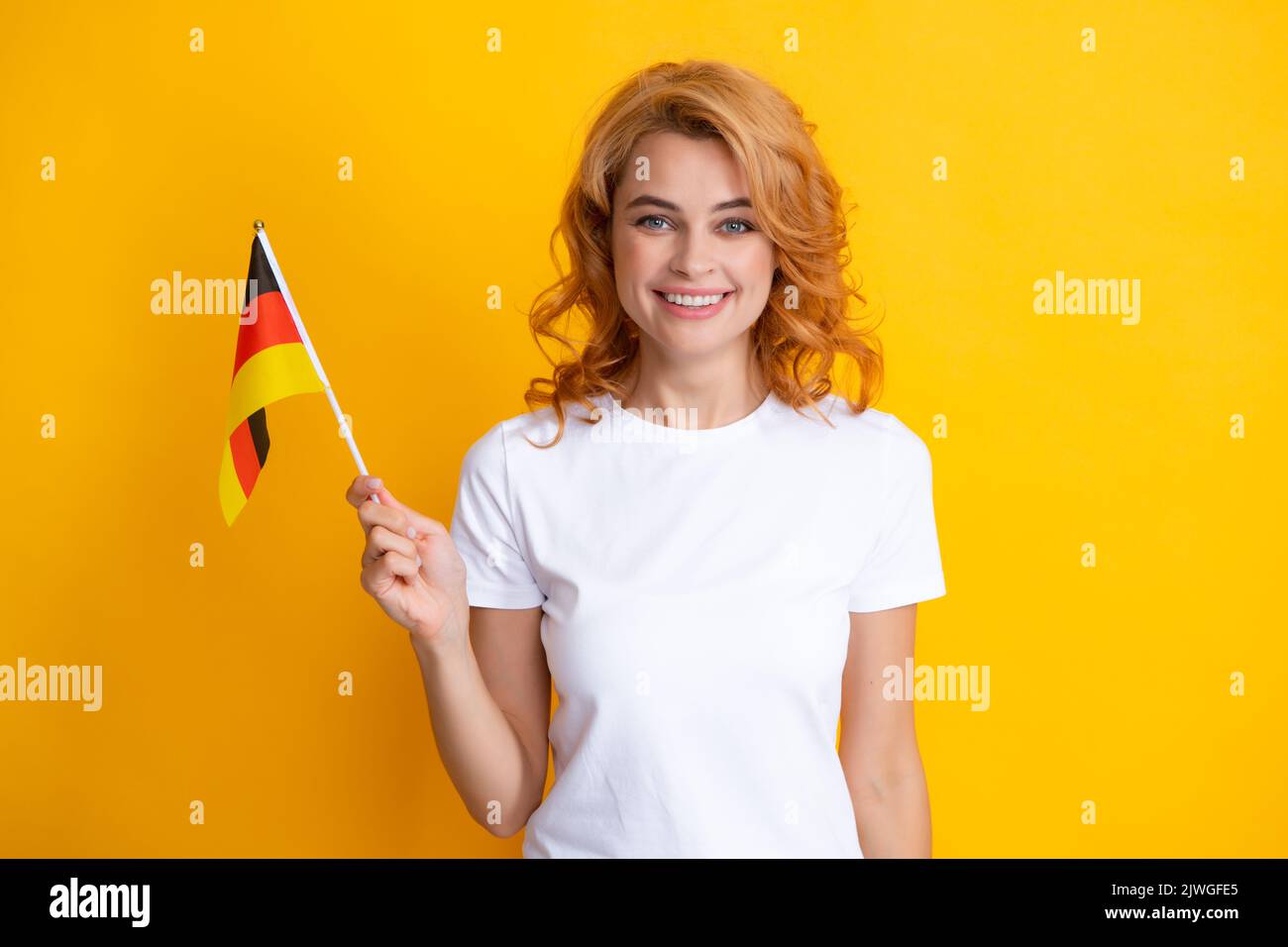 Portrait of happy student woman holding German flag. Isolated on yellow ...