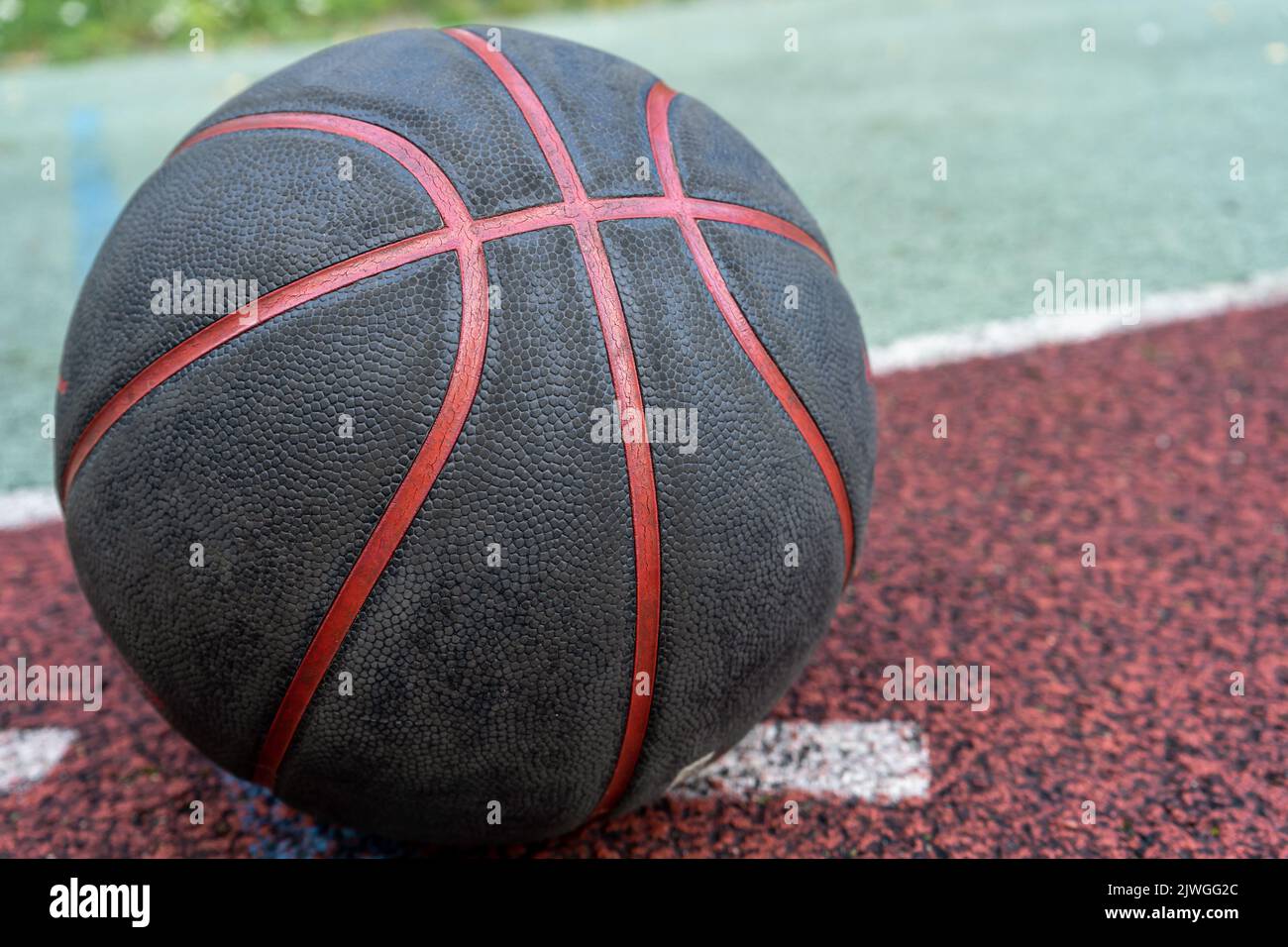 Black basketball ball on the ground. Close-up ball on the red court ...