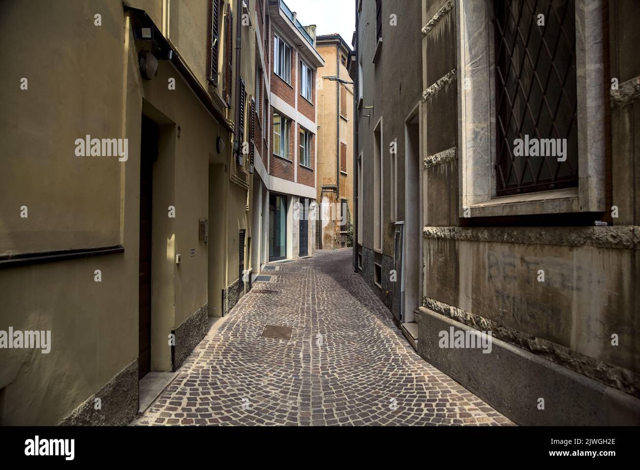 Narrow alley between tall buildings on a cloudy day Stock Photo - Alamy