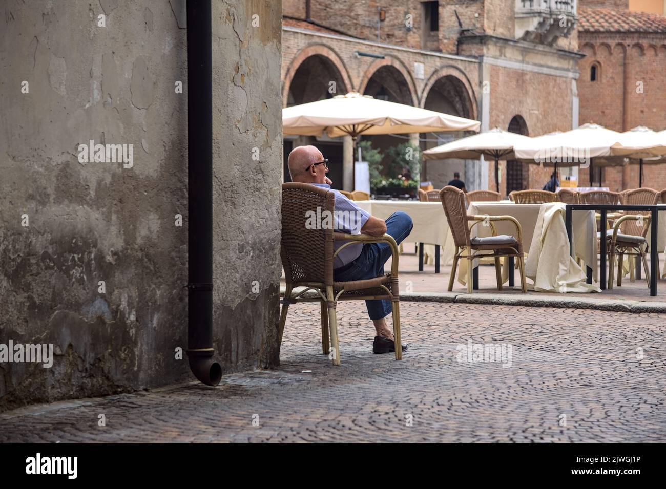Old man sitting on a chair by the corner of a building Stock Photo - Alamy