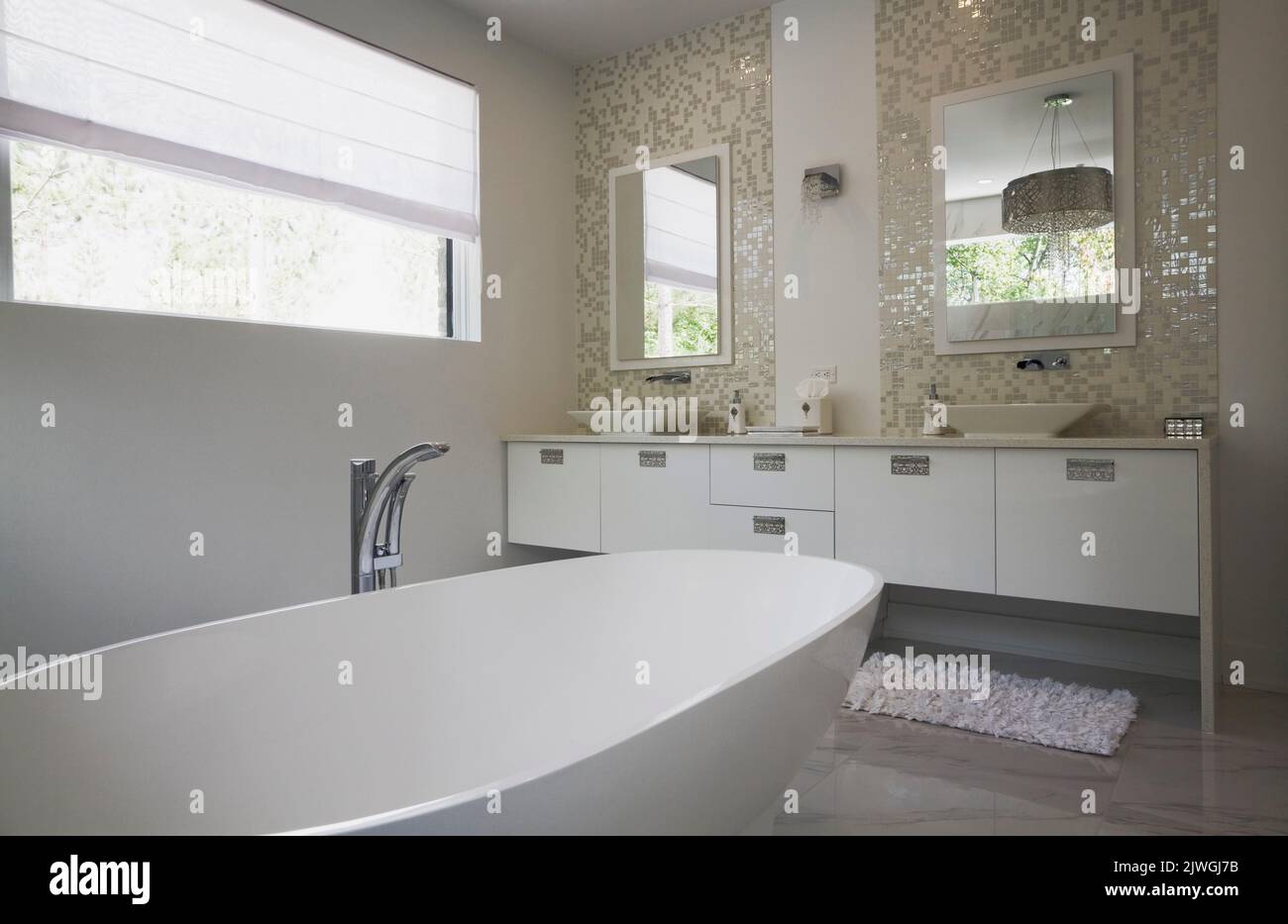 White bathtub and vanity in main bathroom inside luxurious residential ...