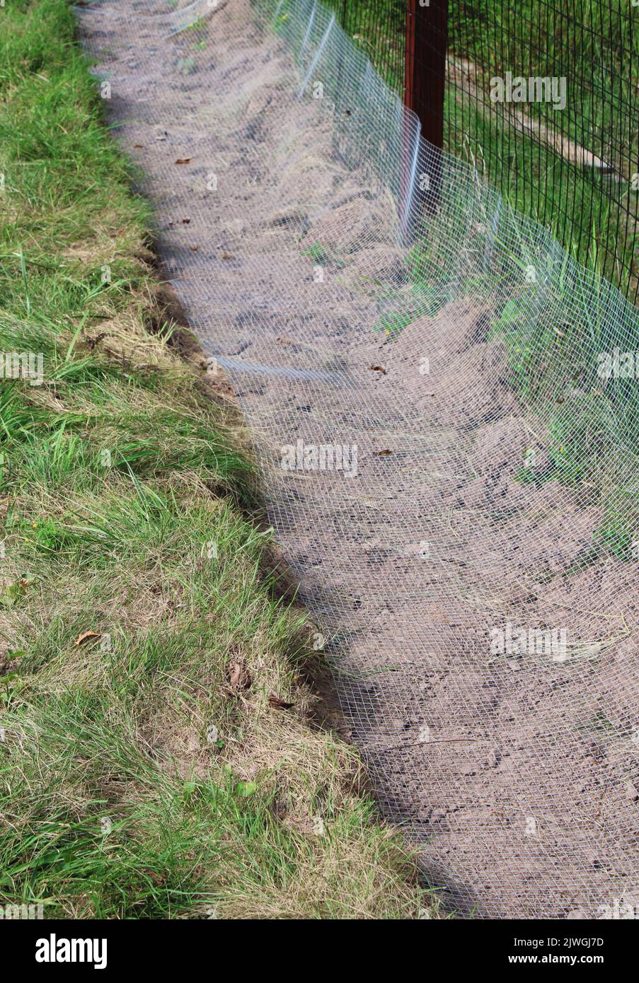 A Wire Fence Laid in a Dug Trench Next to a Garden Stock Photo - Alamy
