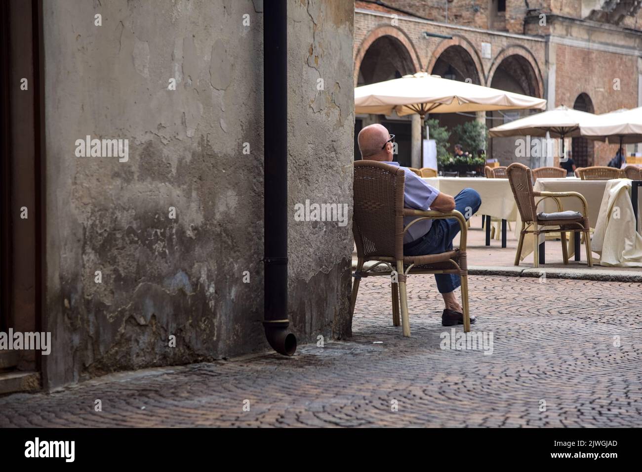 Old man sitting on a chair by the corner of a building Stock Photo - Alamy