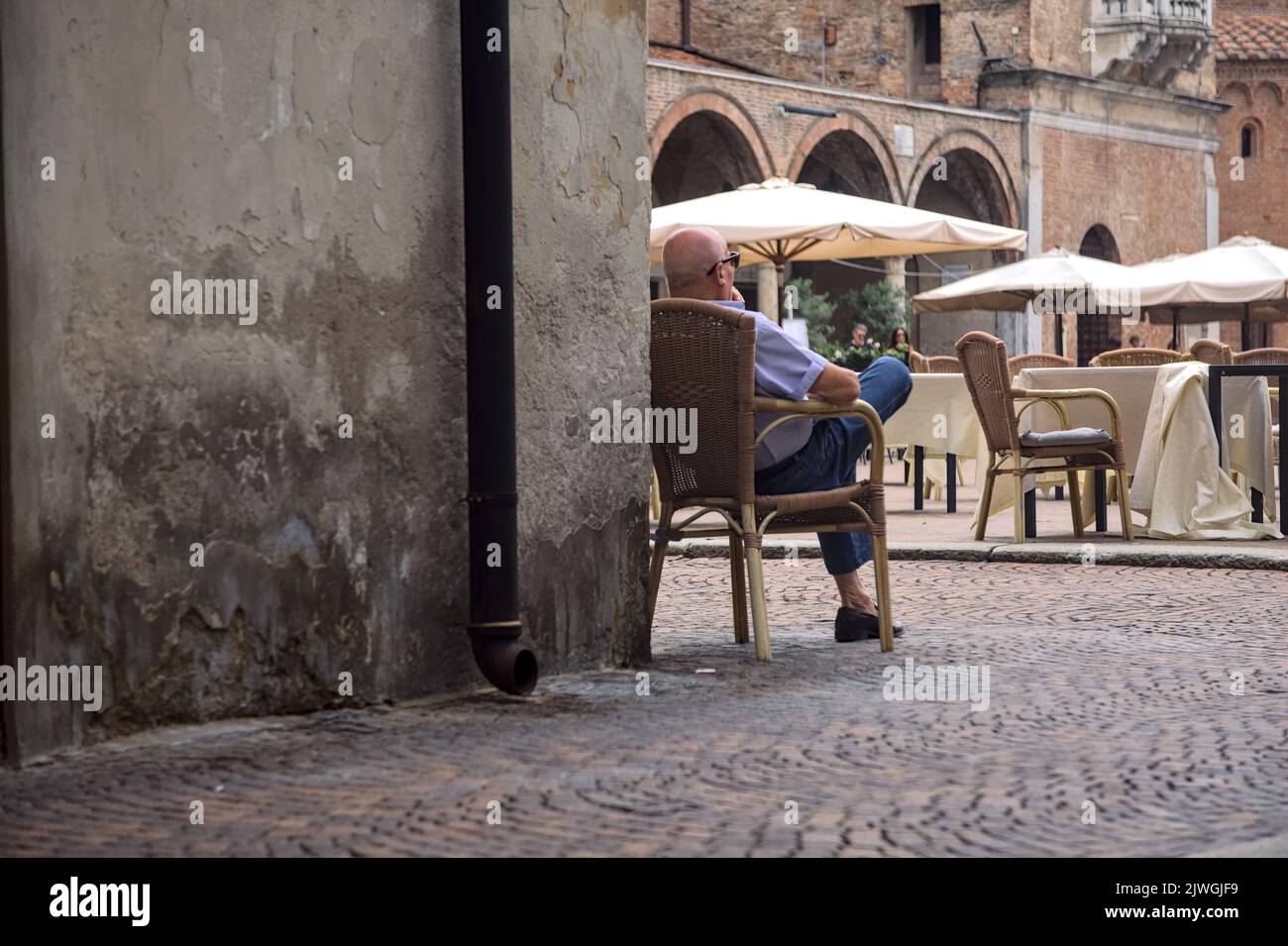 Old man sitting on a chair by the corner of a building Stock Photo - Alamy