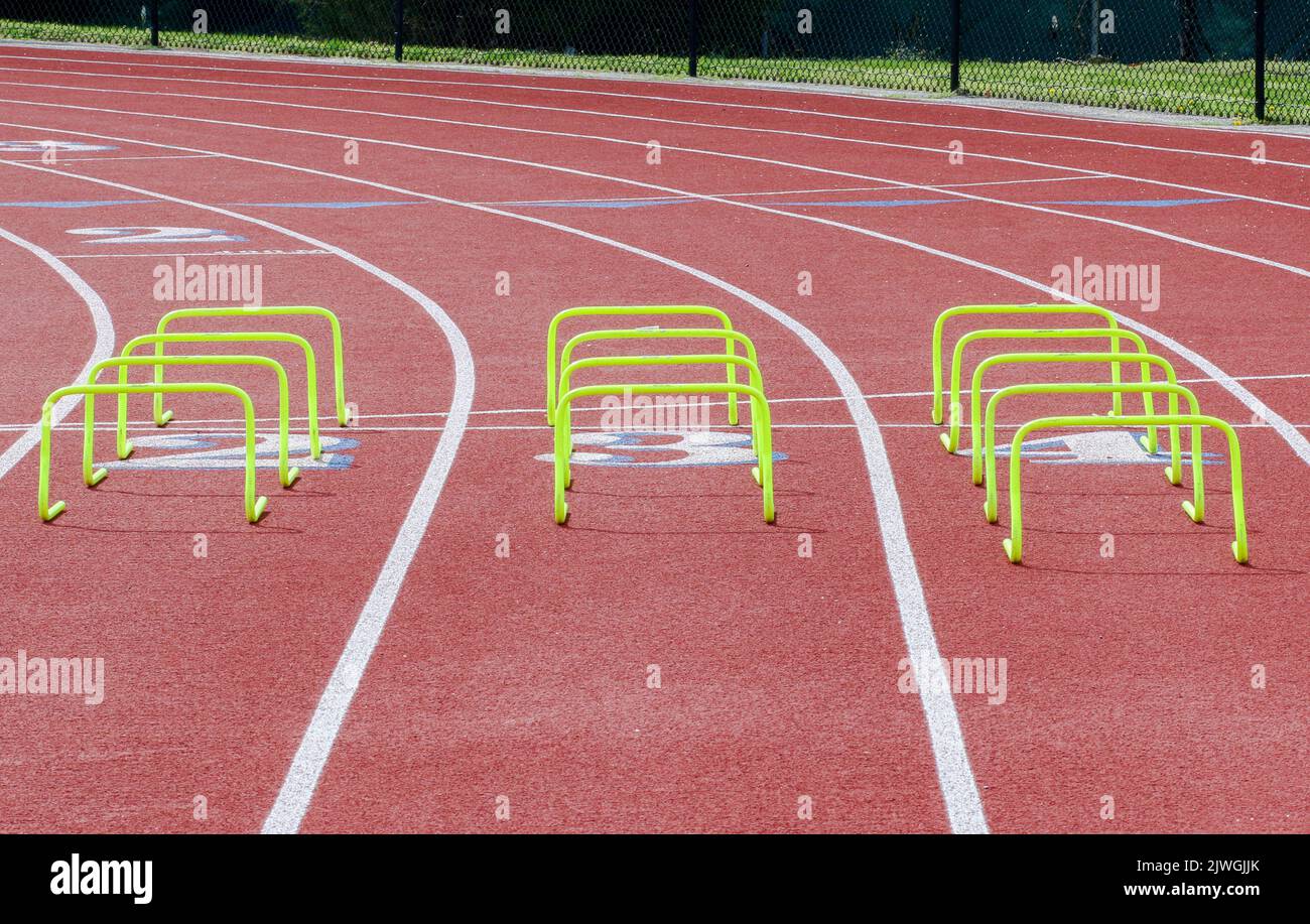 Three rows of yellow mini hurdles set up on a red track for runners agility practice Stock Photo ...