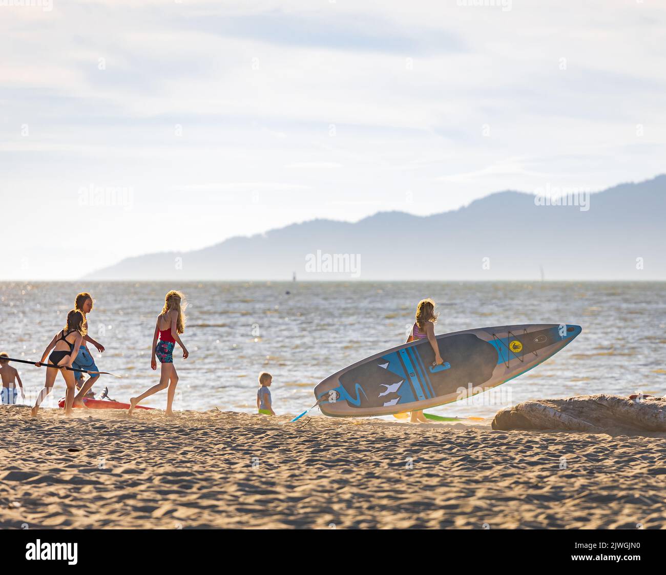 Happy children with SUP at the beach on vacation. Active family riding ...