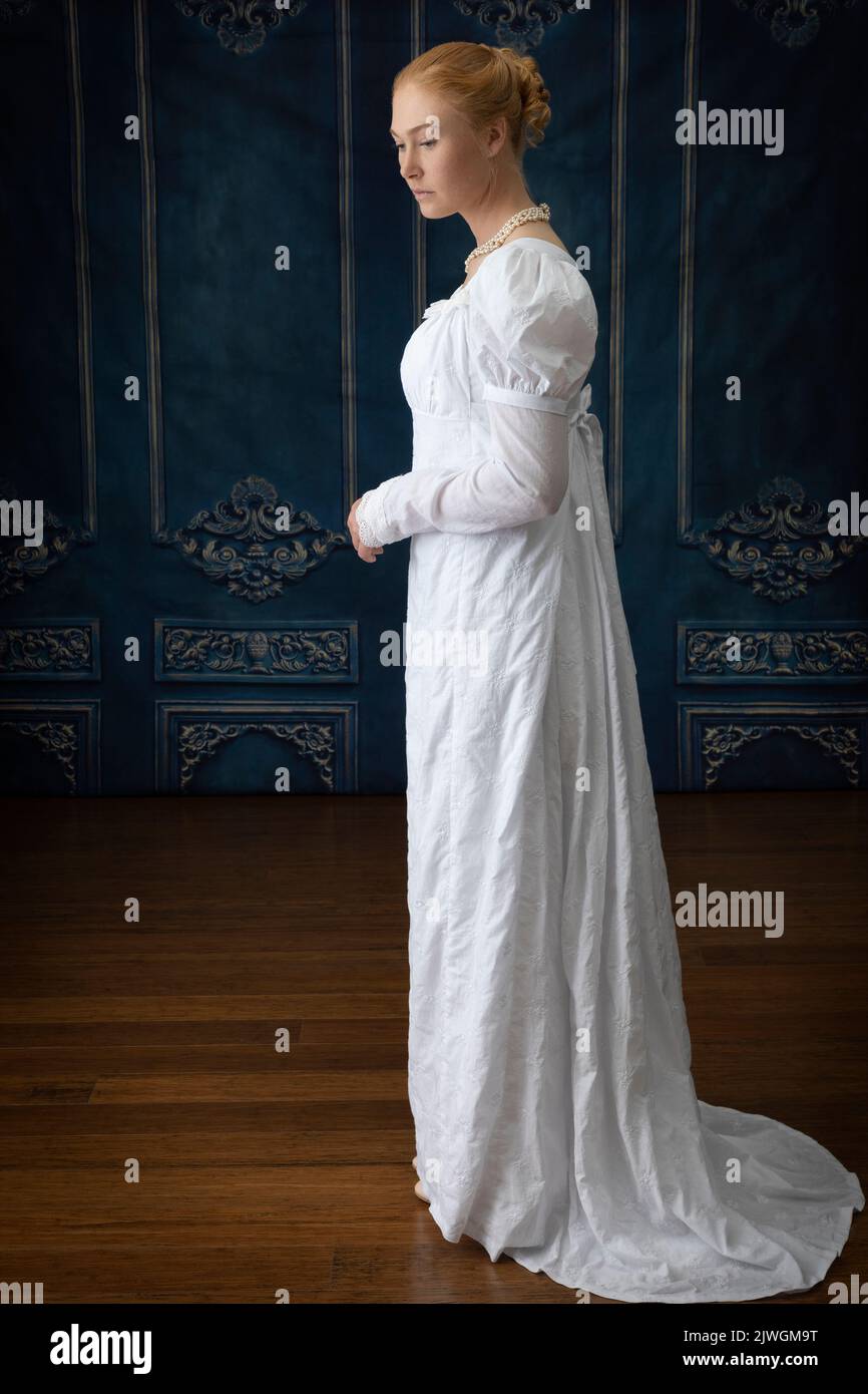 A Regency woman wearing a white embroidered muslin gown with a pearl ...