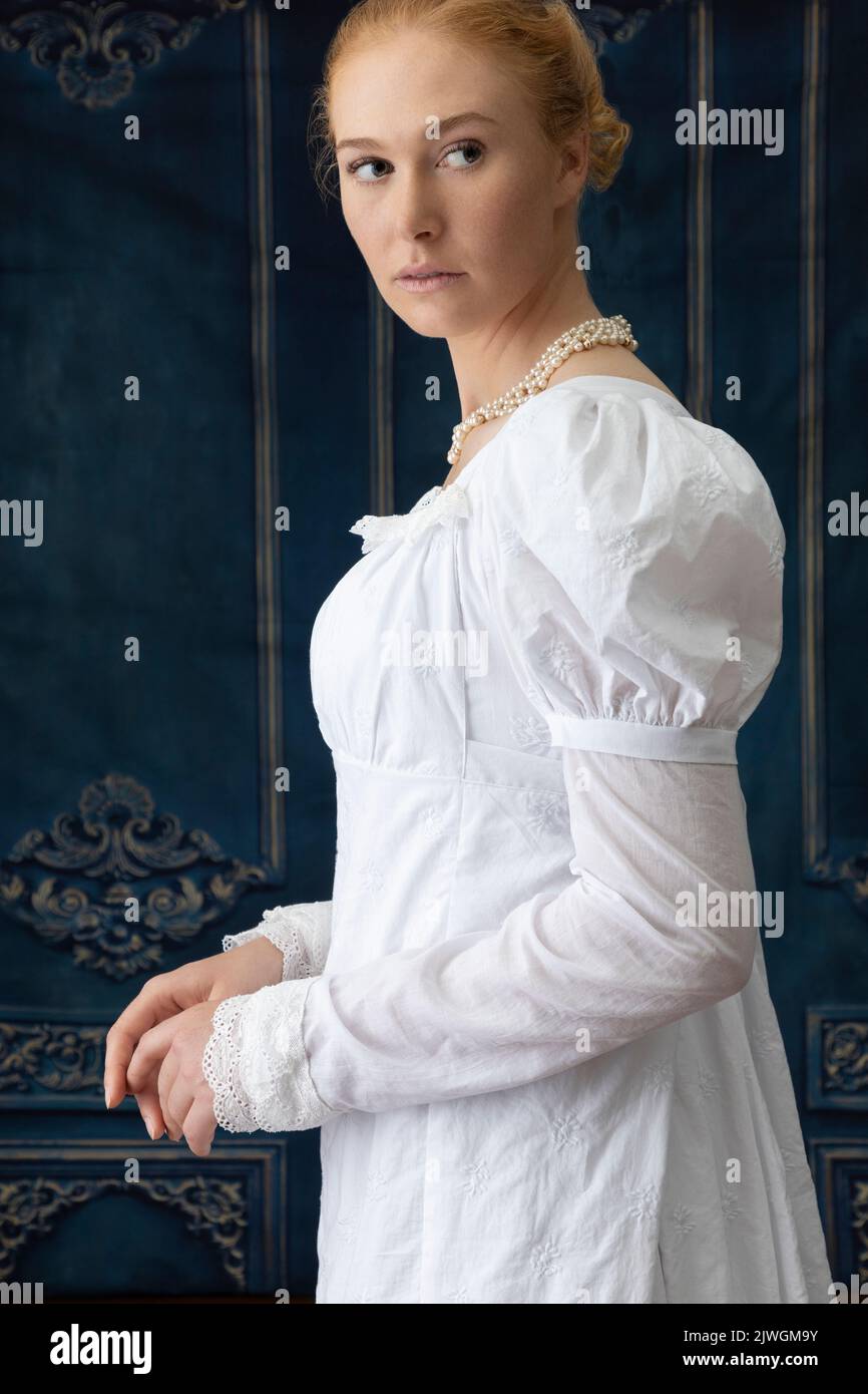 A Regency woman wearing a white embroidered muslin gown with a pearl ...