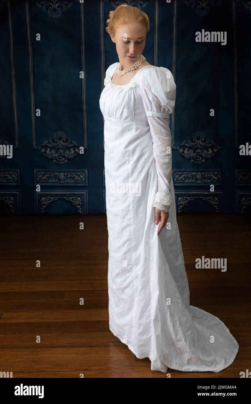 A Regency woman wearing a white embroidered muslin gown with a pearl ...