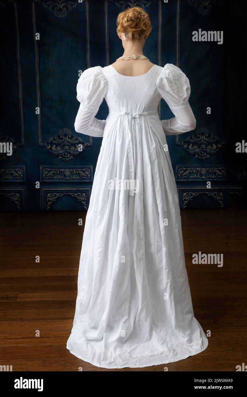 A Regency woman wearing a white embroidered muslin gown with a pearl ...
